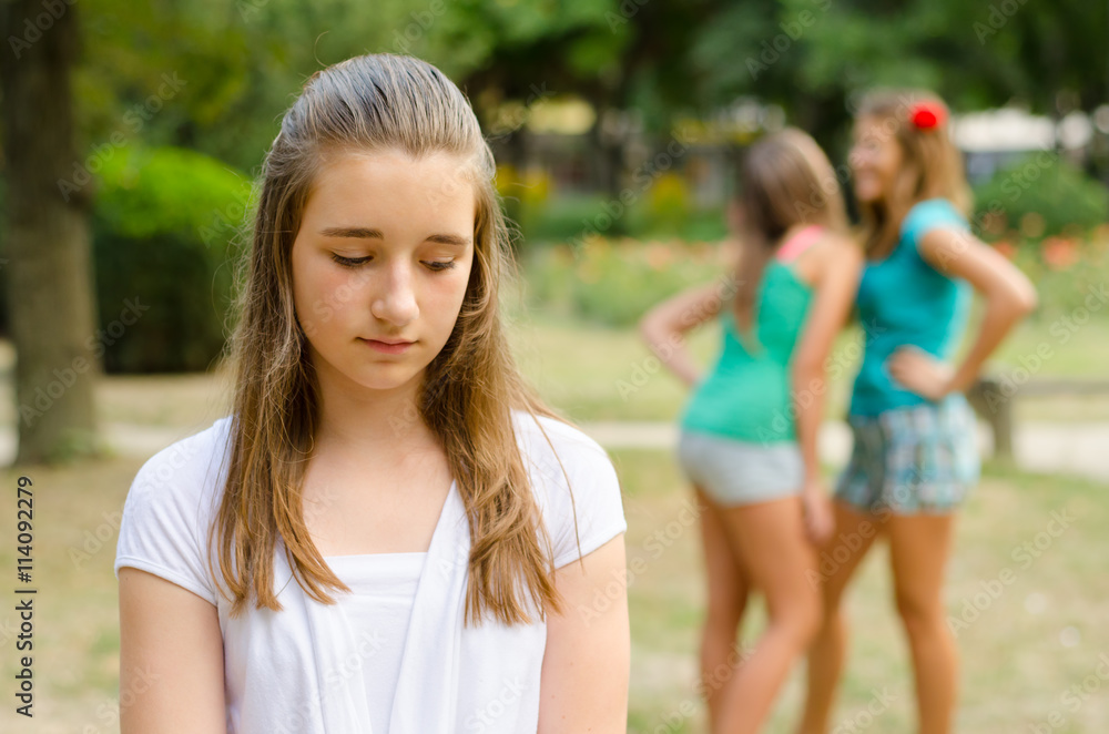 Sad teenage girl rejected by other teenage girls Stock Photo | Adobe Stock