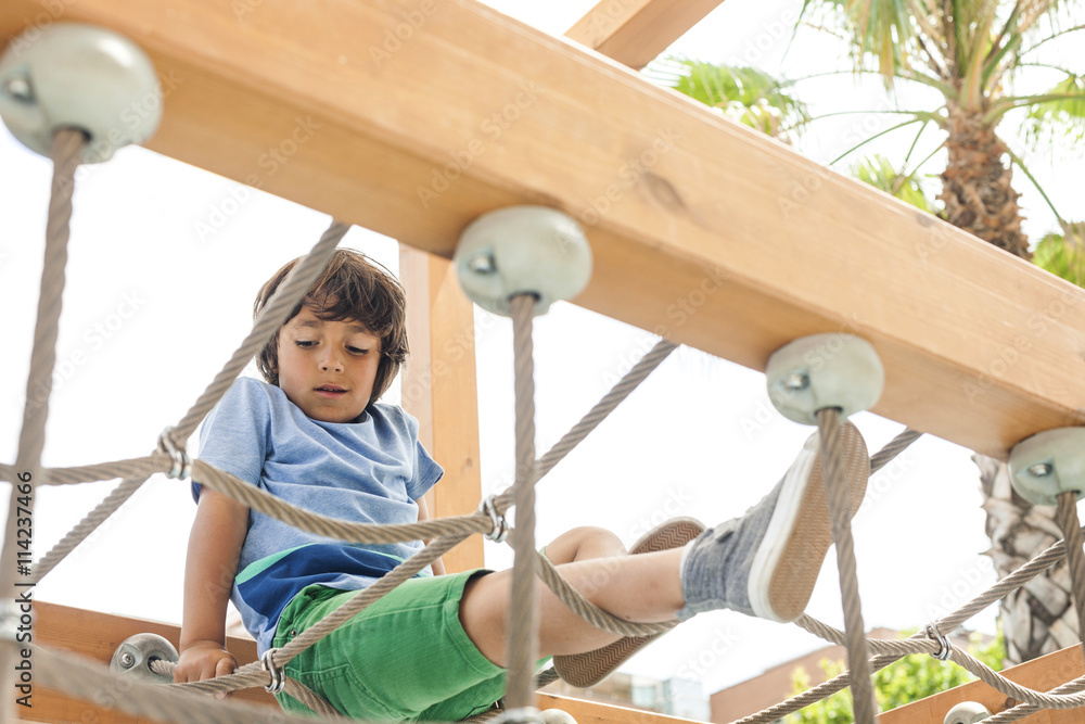 Little boy climbing on hanging bridge of a playground Stock Photo ...