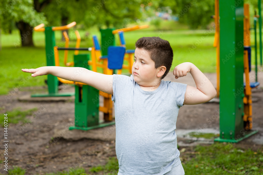 fat boy shows his muscles in background of exercise equipment Stock ...