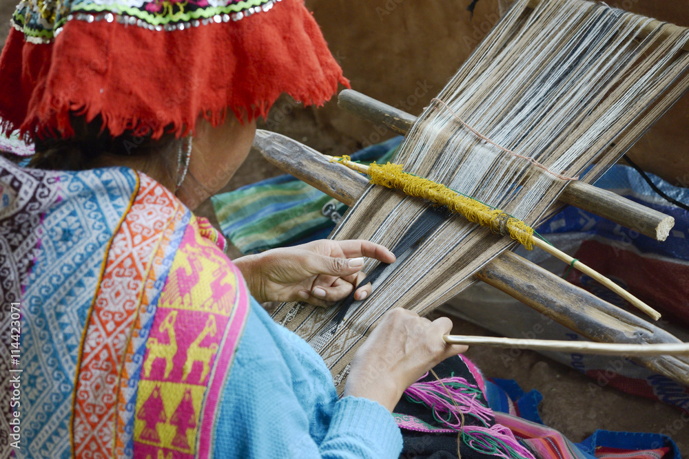 Peruvian woman in traditional clothing weaving cloth on a hand loom ...