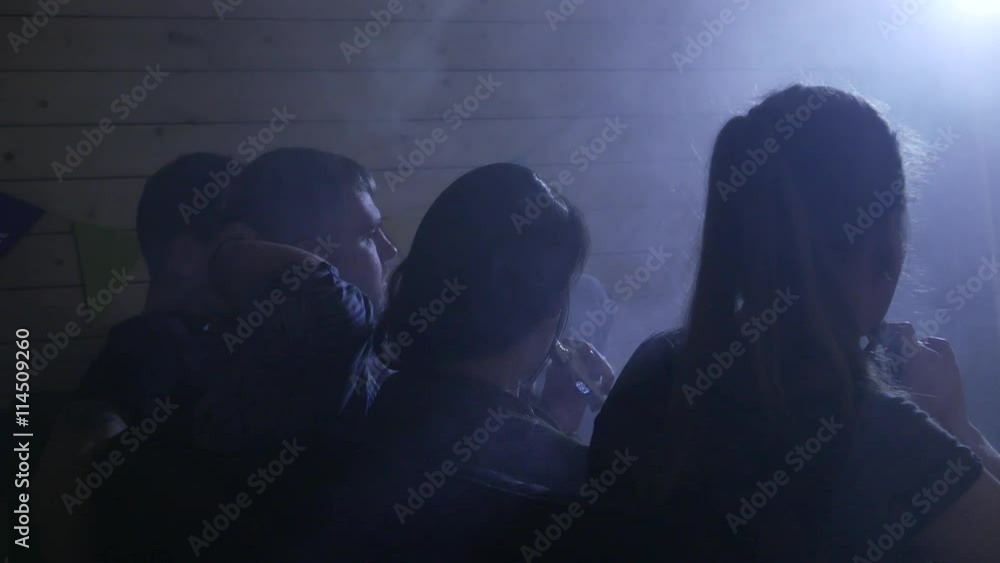 A group of people vaping, inhaling and exhaling large clouds of smoke ...