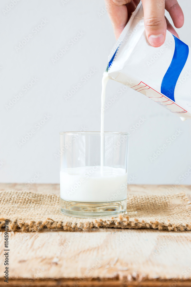 Hand holding a carton of milk poured into a glass on white backg Stock ...