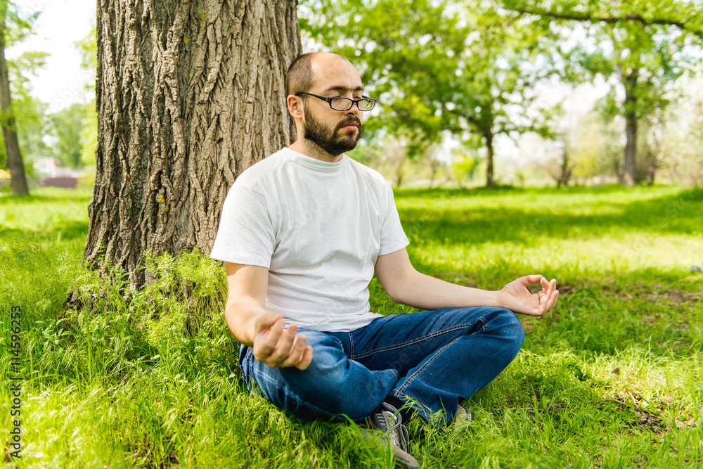Man meditating under a tree. foto de Stock | Adobe Stock