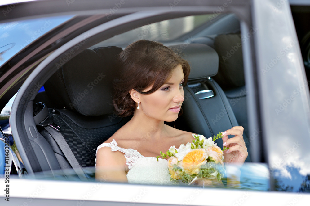 Beauty bride in bridal gown with bouquet and lace veil in the car ...