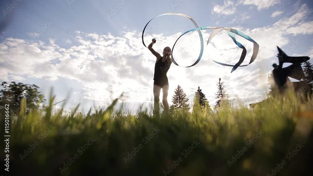 Dance young gymnast with ribbon on sunset sky background. Rhythmic ...