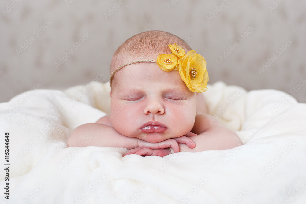 Closeup portrait of newborn child with a yellow flower on the head ...
