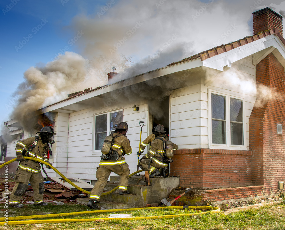 Fire fighters in full breathing apparatus enter a smoke filled house on ...