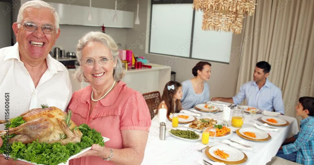 Proud grandparents holding roast chicken with family behind them Stock ...