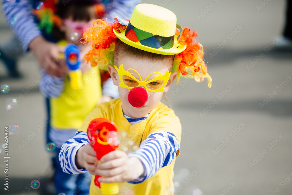 Little boy in clown costume blowing bubbles outdoors at summer day ...