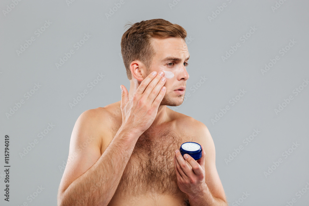 Young man putting cream lotion on face Stock Photo | Adobe Stock