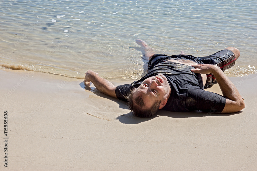exhausted man crawled out of the sea and lying on the beach Stock Photo ...