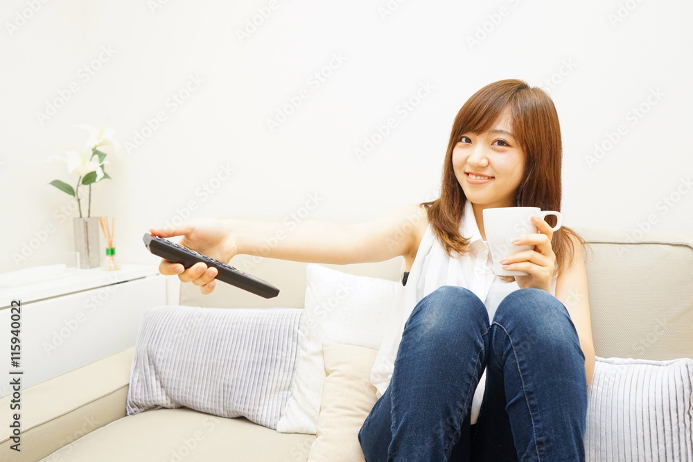Young japanese woman holding a remote controler of TV テレビのリモコンを持ちチャンネルを ...
