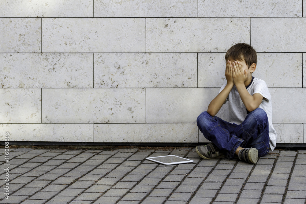 Little boy sad, tired and stressed with tablet computer PC. Kid sitting ...