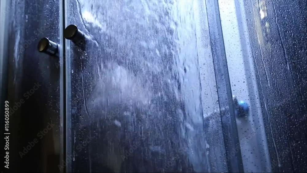 Showering woman silhouette blurred by the transparent door. woman ...