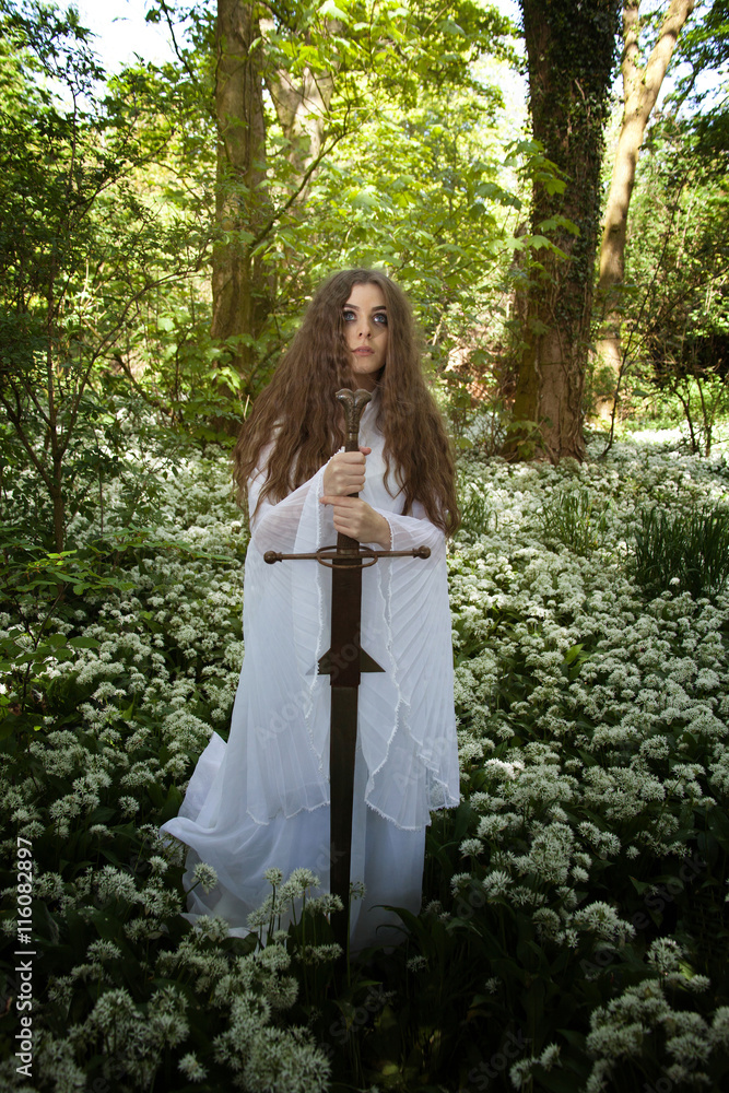 Beautiful woman wearing a long white dress holding a medieval sword ...