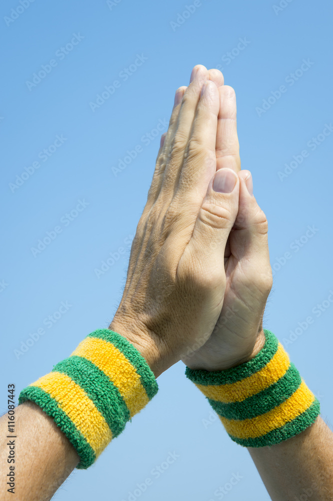 Hands of a Brazilian athlete wearing Brazil colors wristbands praying ...