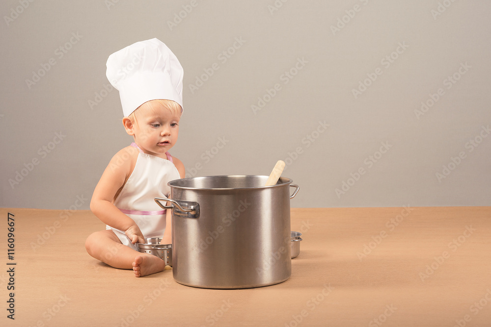 Charming and surprised kid in an apron and chef hat sitting next to a ...