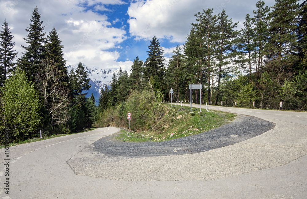 A steep turn on a mountain road with road signs "speed limit" and "no ...