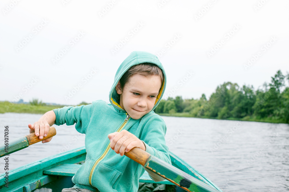 boy rowing a boat in the middle of the river. child enjoys boating and ...