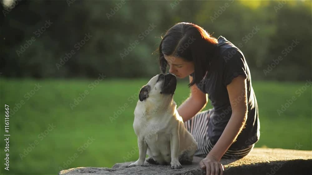 Young beautiful woman blowing a kiss to her dog at the park, Cute Mops ...