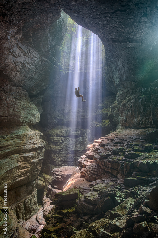 The mist in a dark wet cave is naturally lit by shafts of light coming ...