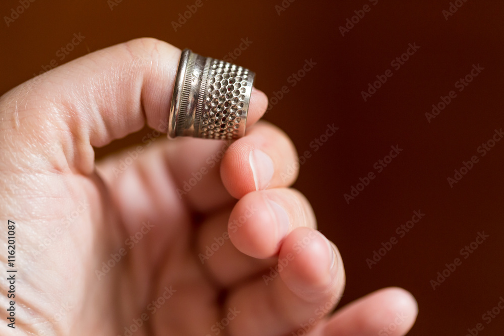 thimble on thumb of hand with red background Stock-Foto | Adobe Stock