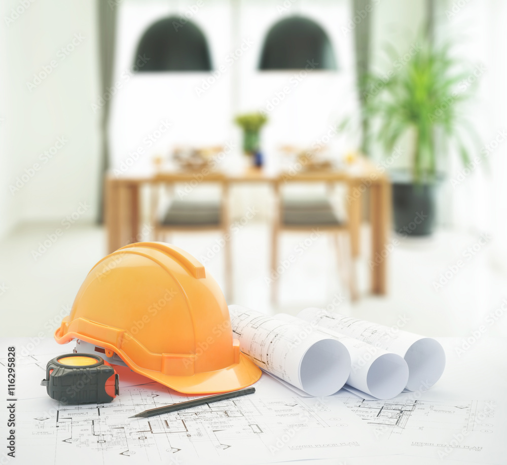 architectural blueprint with safety helmet and tools over dining table ...