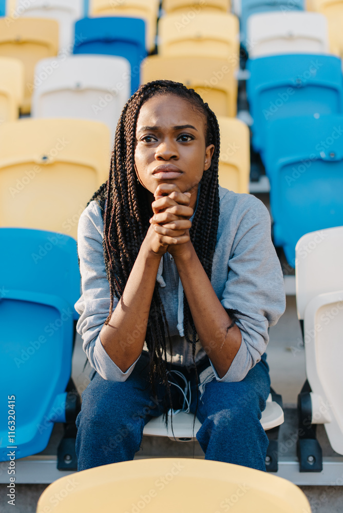 Worried african american young woman sitting waiting in rows of empty ...
