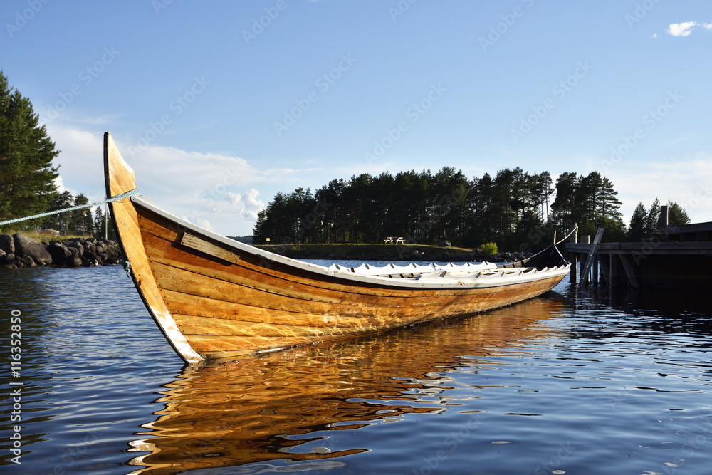 Long rowing boat laying in the water with blue sky in background ...