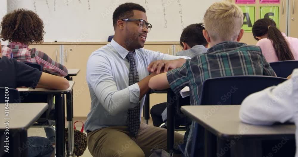 Teacher kneeling down to help a boy at his desk, Stock-Video | Adobe Stock