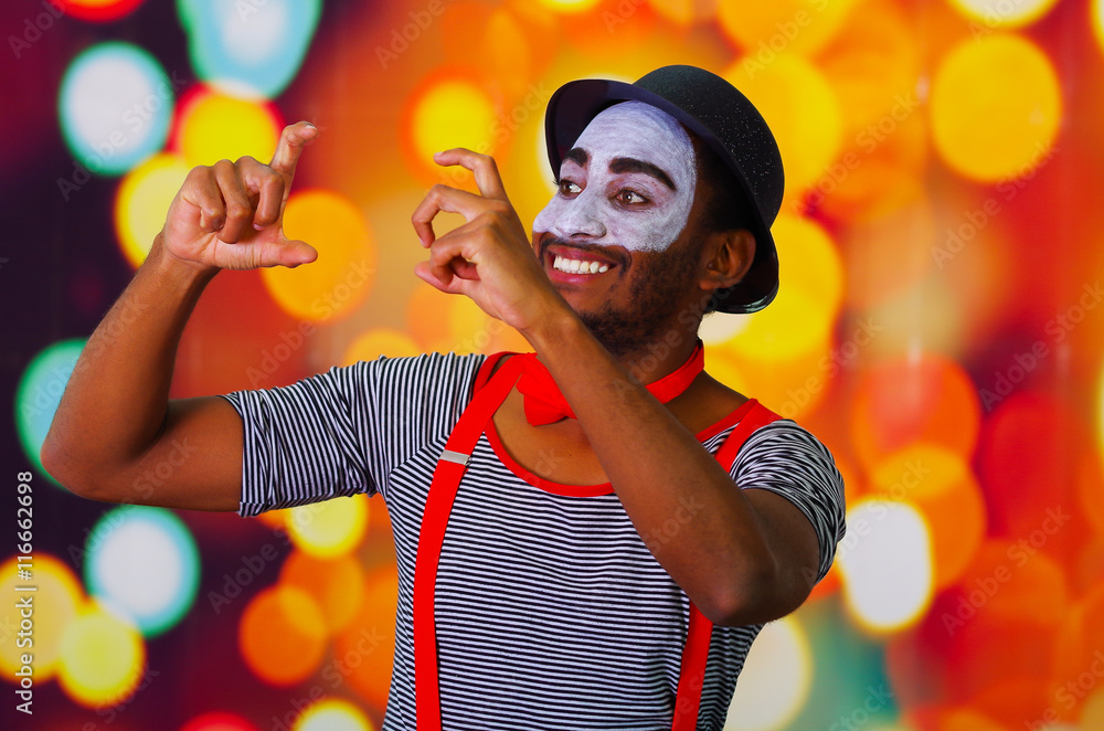 Pantomime man wearing facial paint posing for camera, using hands ...