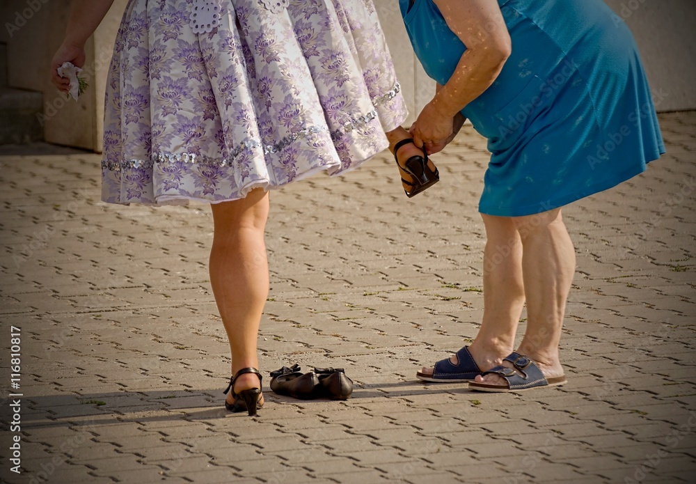 Legs mother and daughter./ Mother on slippered fastens the shoe of his ...