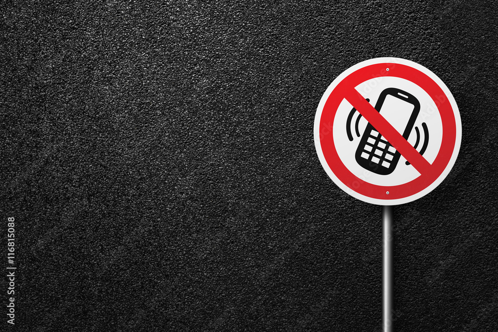 Road sign of the circular shape on a background of asphalt. No phones ...