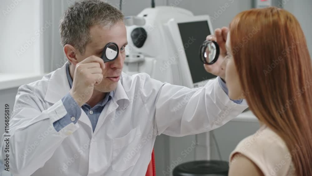Optometrist examining eyes of female patient using indirect ...