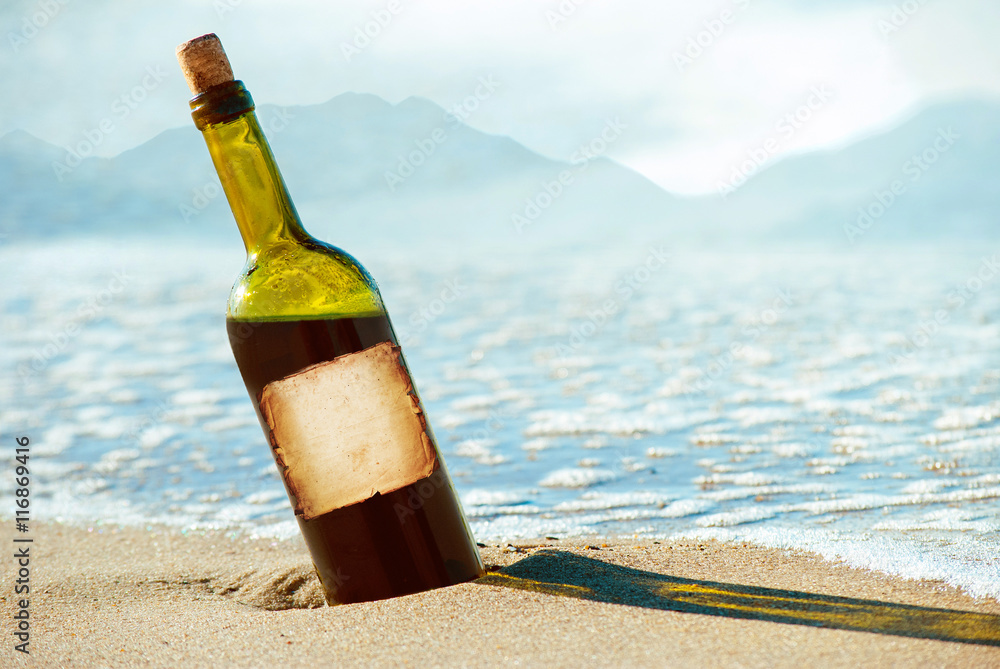 Alcohol bottle with old paper label in the sand on a tropical beach ...