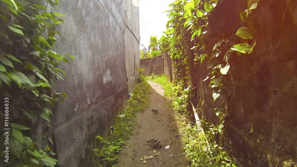 Walking along a long, narrow alleyway between cement walls, marking the ...