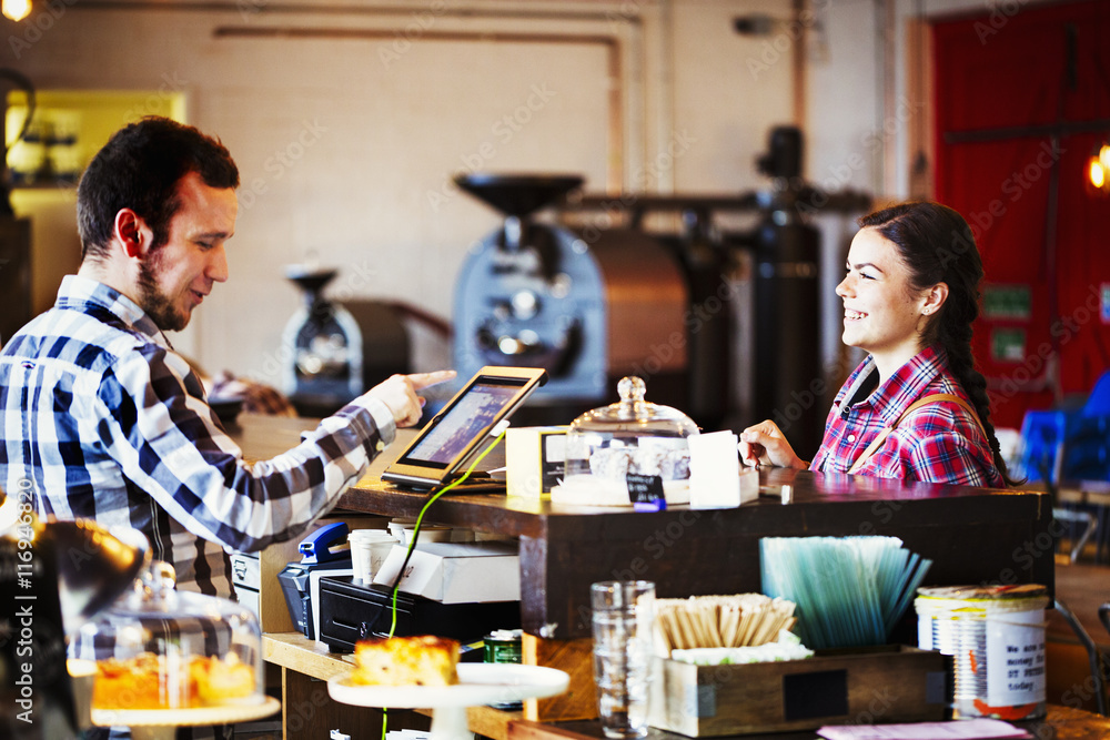 Specialist coffee shop. A man behind the counter using a touch screen ...