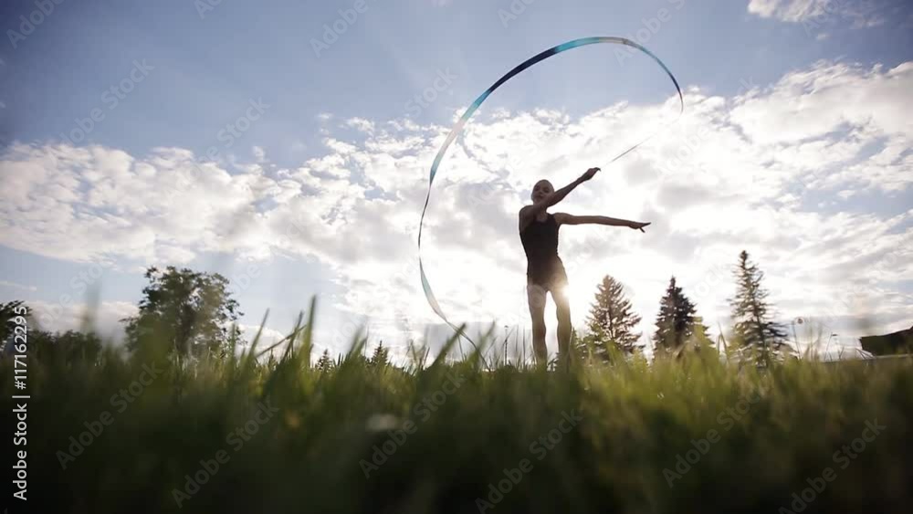 Dance young gymnast with ribbon on sunset sky background. Rhythmic ...