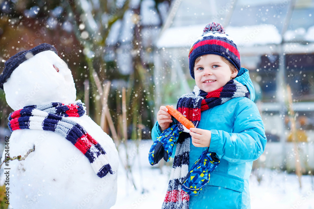 Little kid boy making a snowman in winter Stock Photo | Adobe Stock