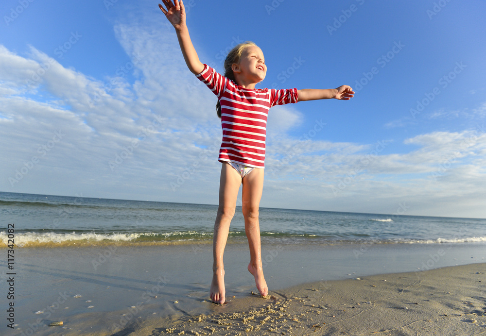 Beautiful little happy girl playing, having fun on the beach in daytime ...