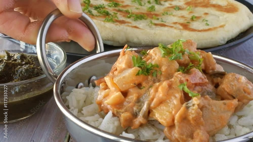 Indian woman serve a traditional Indian butter chicken curry with ...