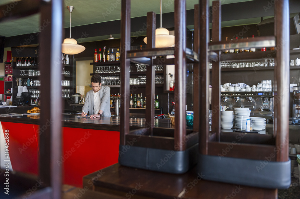 Man behind counter of a cafe taking notes Stock Photo | Adobe Stock