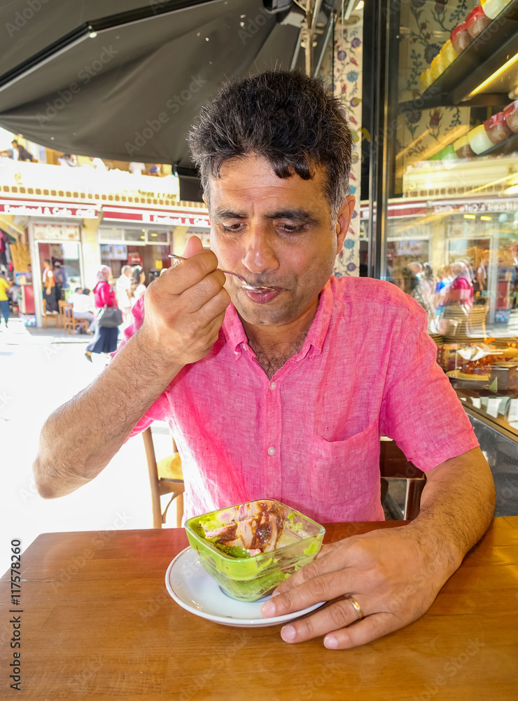 Indian man eating pudding in Istanbul Stock Photo | Adobe Stock