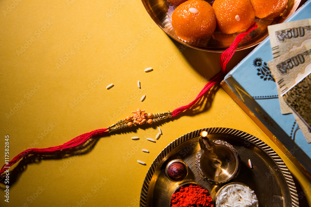 Rakhi and diya in a puja thali with gift box, indian currency notes ...