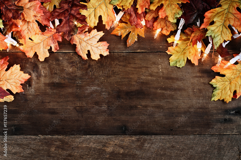 Rustic fall background of autumn leaves and decorative lights over a ...