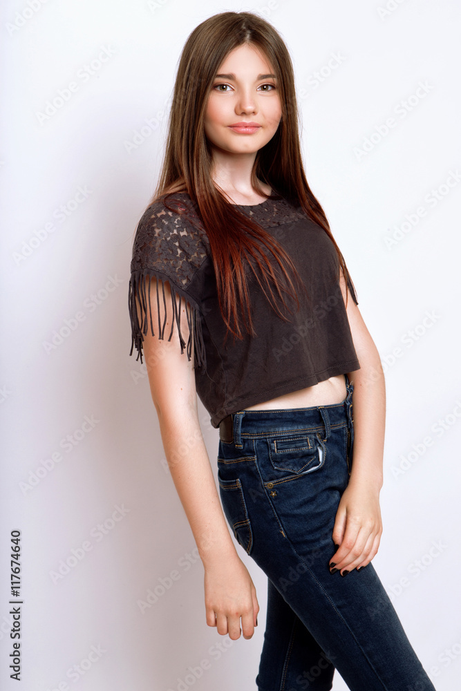 A beautiful 13-years old girl dressed in jeans and T-shirt in studio on ...