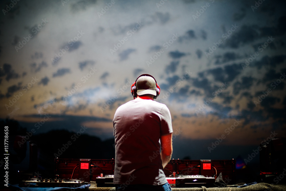 Club, disco DJ playing and mixing music for crowd of happy people ...