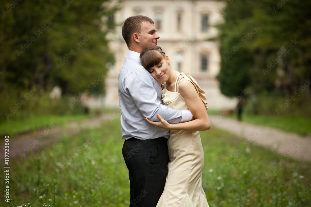 Gorgeous woman in beige dress lies her head on man's chest stand Stock ...