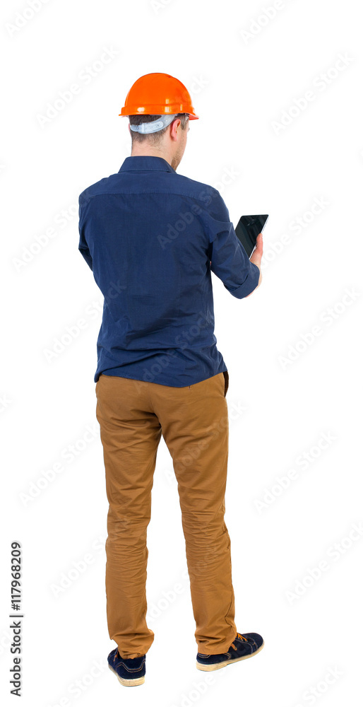 Backview of business man in construction helmet stands and enjoys ...