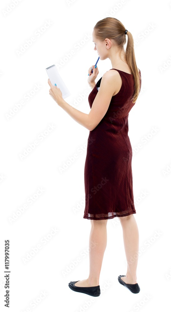 back view of stands woman takes notes in a notebook. girl watching ...